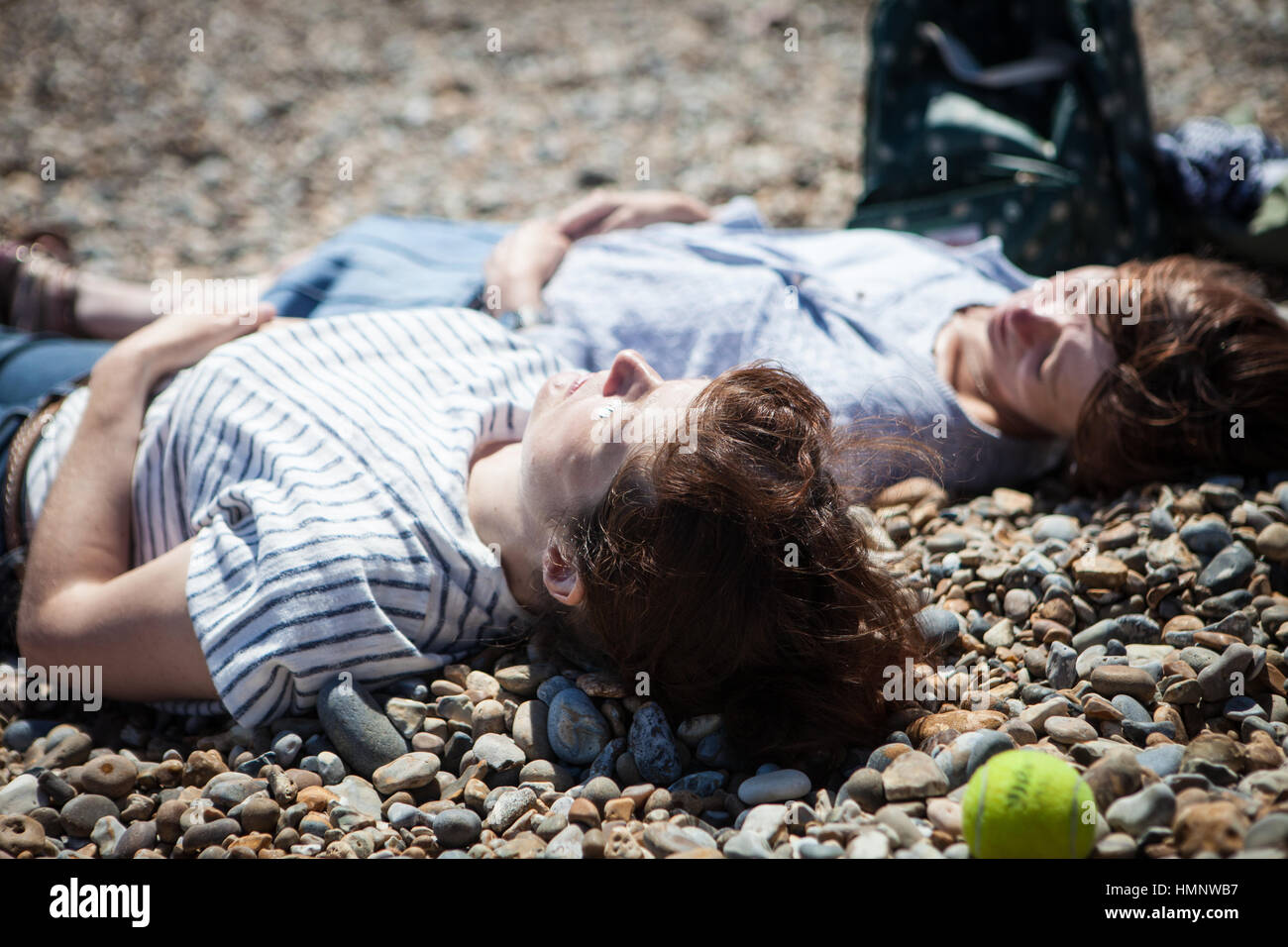 Two women sunbathing on pebble beach Stock Photo - Alamy