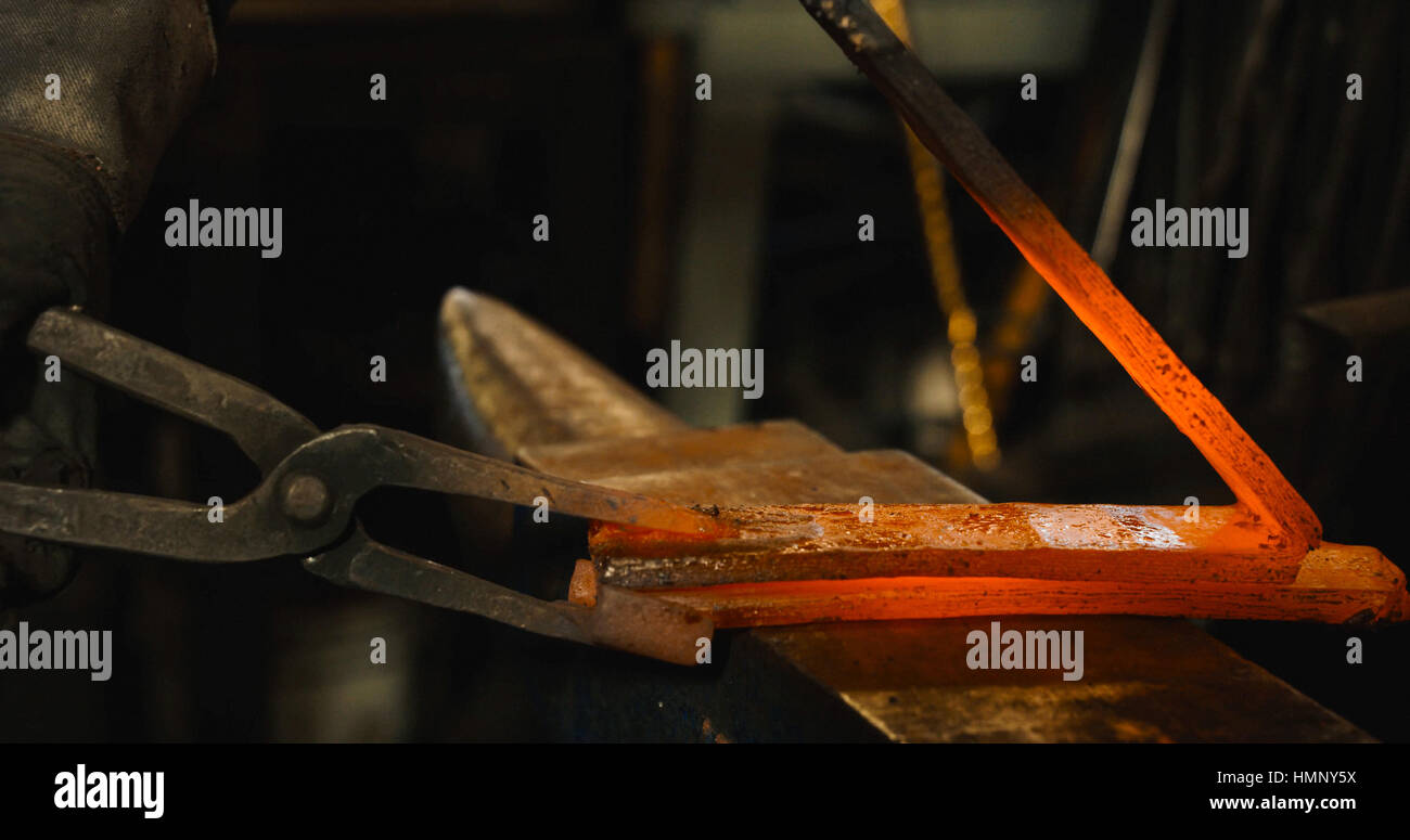 Rod hot iron on the anvil ready to be beaten Stock Photo - Alamy
