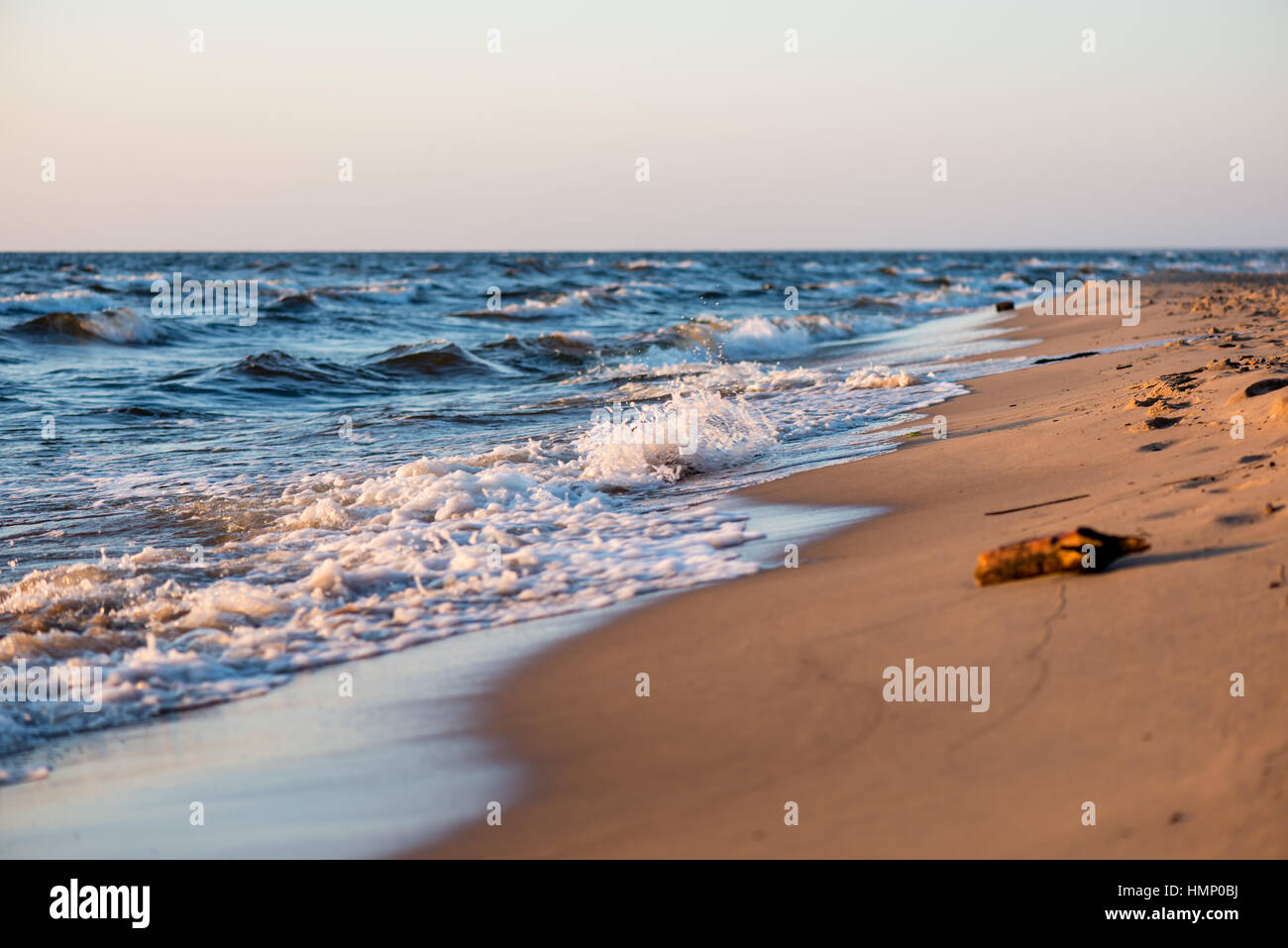 red and orange dramatic sunset on the sea beach with old tree trunk ...