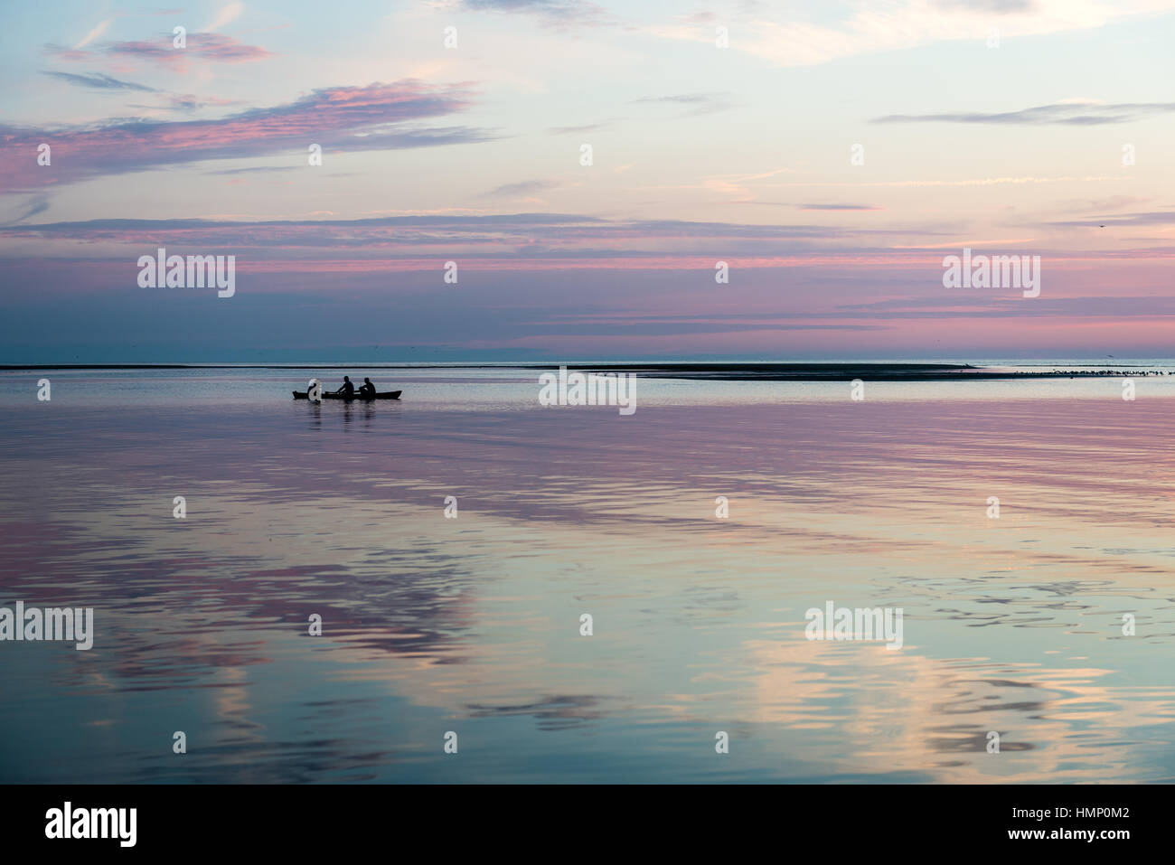 Reflections in the calm lake water with dramatic clouds with small boat ...