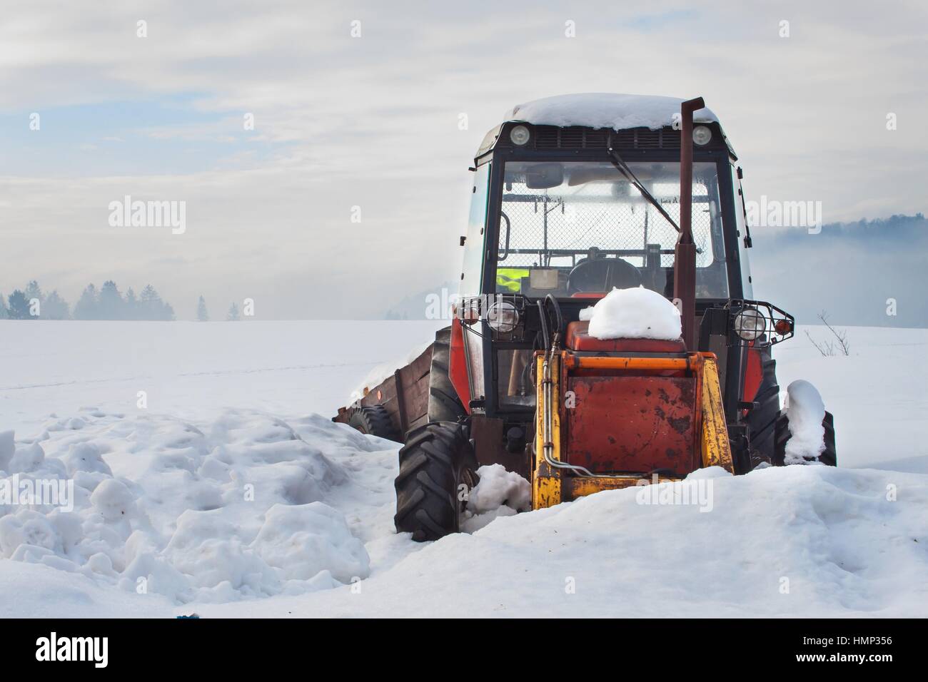 Old tractor under the snow. Snow calamity in transport. Frozen diesel ...