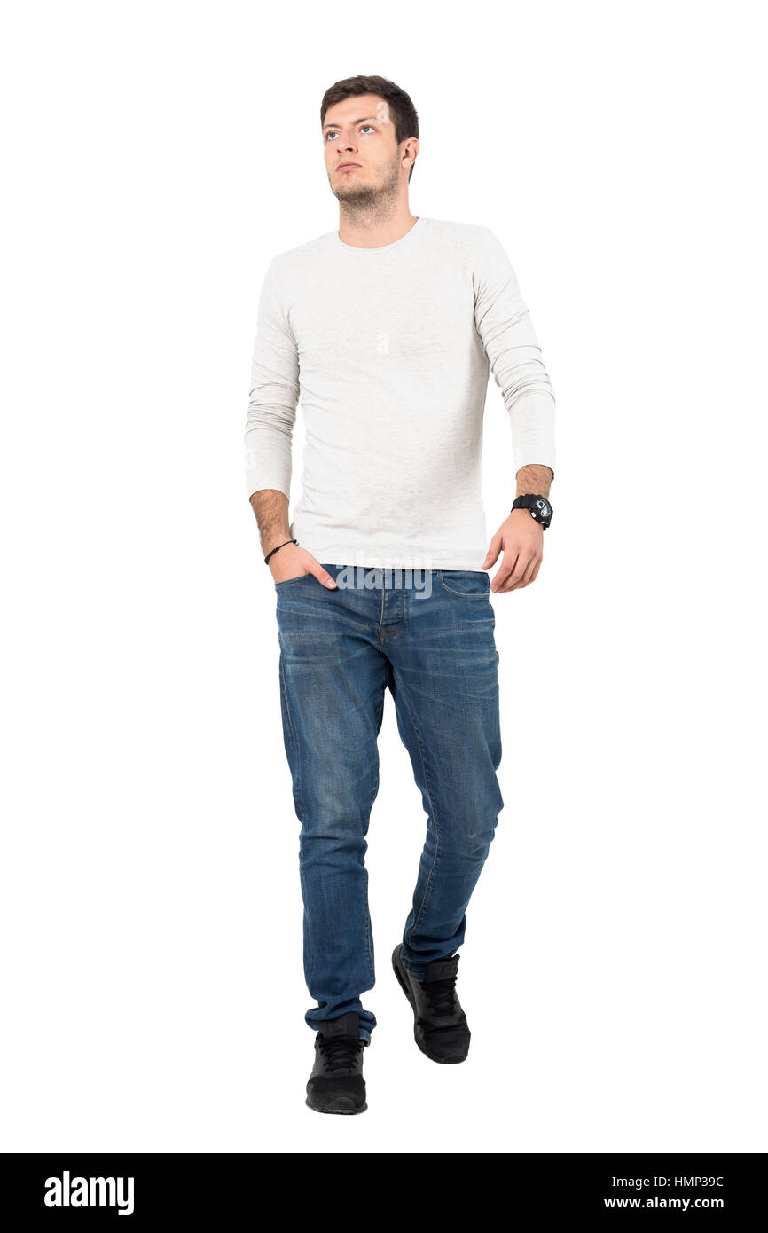 Relaxed young man in casual wear walking towards camera looking up ...