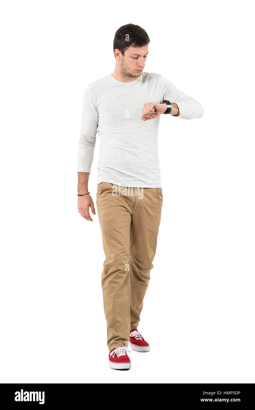 Stylish young man walking and checking time on wrist watch. Full body ...