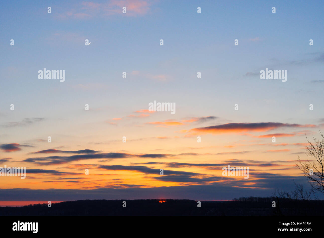 Deep red sun peeking throught trees on horizon during early morning ...