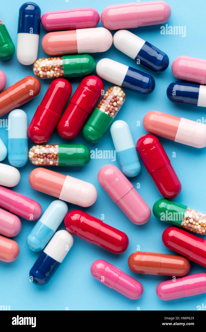 Colorful different medicine capsules on blue background Stock Photo - Alamy