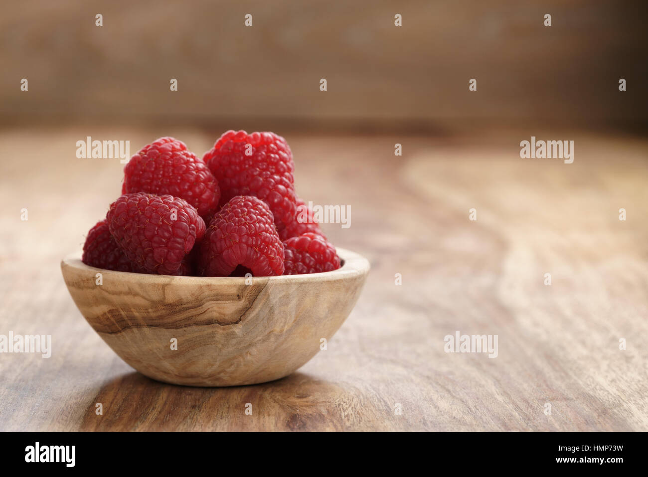 ripe organic raspberries in wood bowl on old wooden table Stock Photo ...