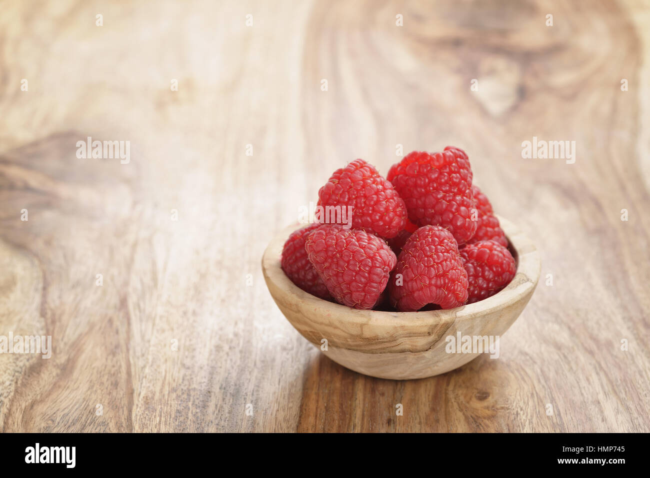 ripe organic raspberries in wood bowl on old wooden table Stock Photo ...