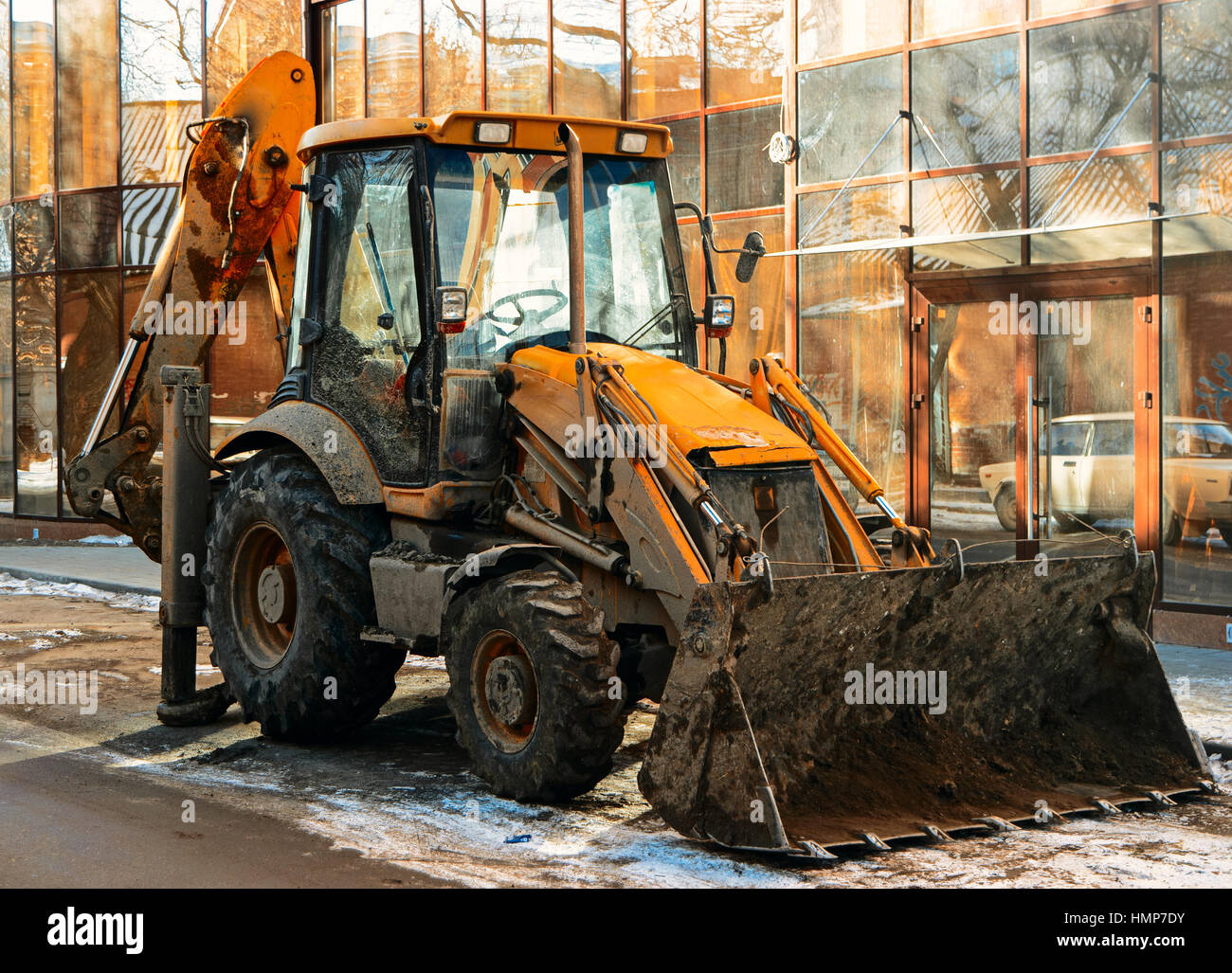 Bulldozer in the street in front of glass wall of modern building Stock ...