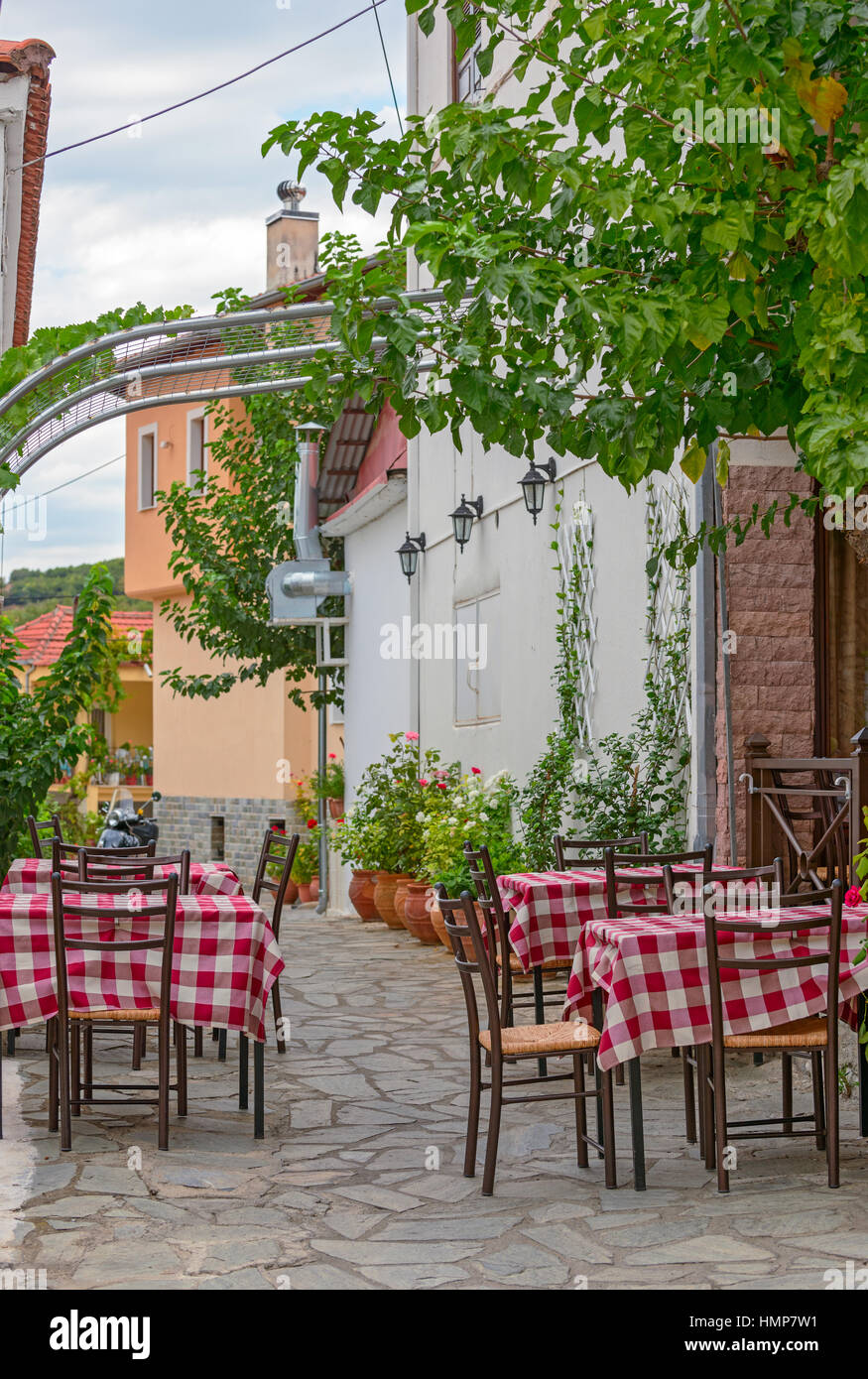 Restaurant tables on street terrace with flowers around Stock Photo - Alamy