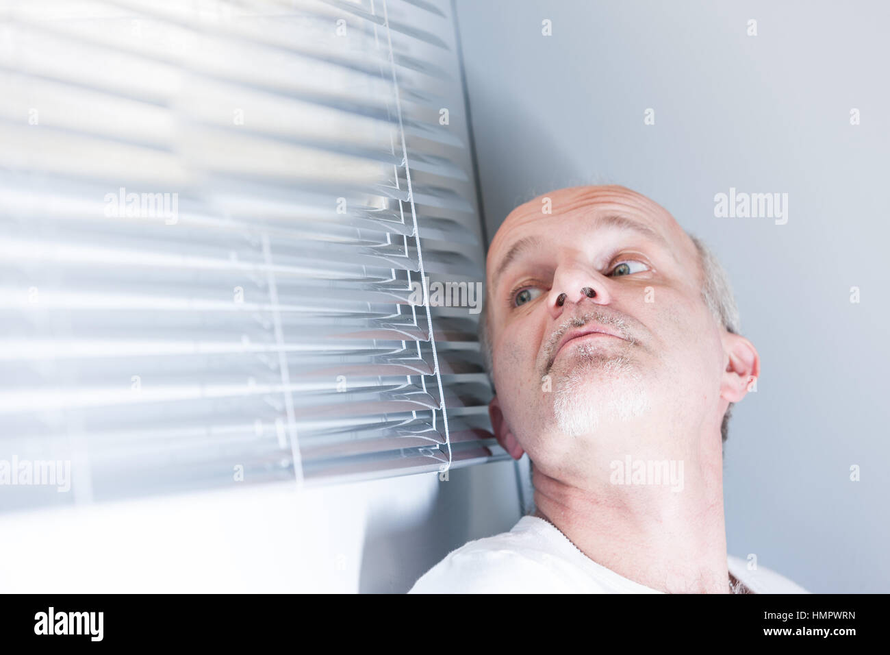senior man at home checking out of his window if there is something or ...