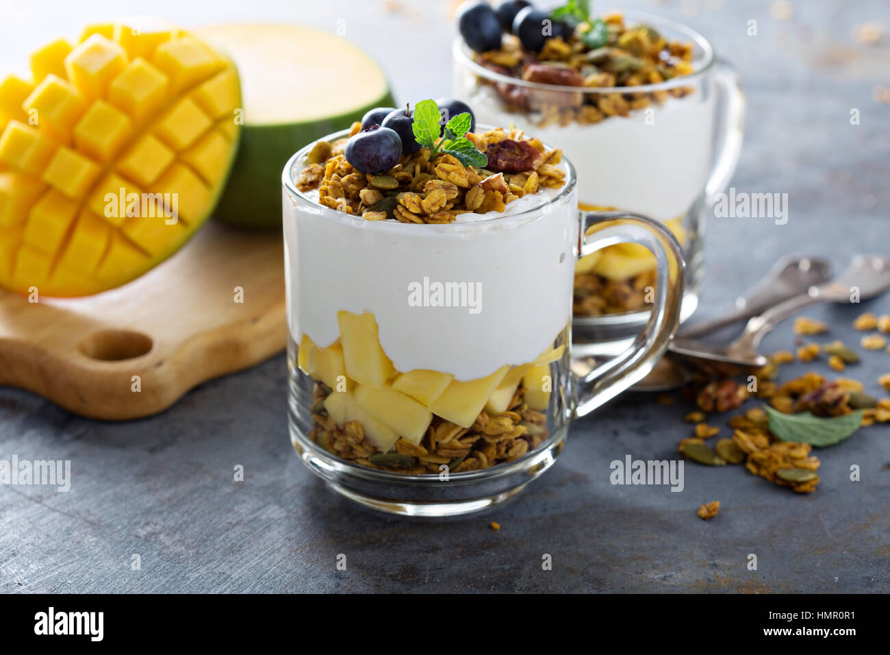 Mango yogurt parfait with granola on top in glass mugs Stock Photo - Alamy