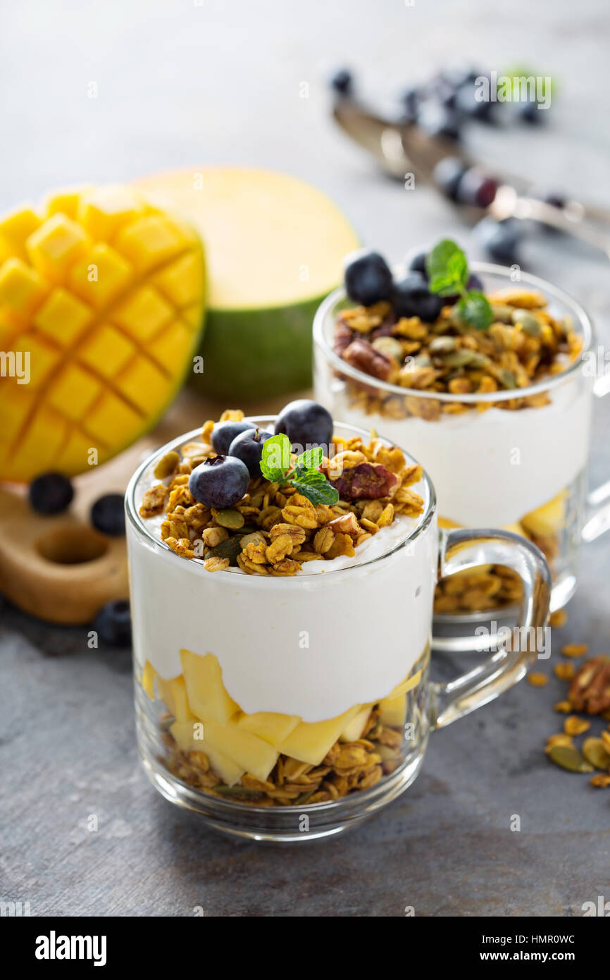 Mango yogurt parfait with granola on top in glass mugs Stock Photo - Alamy