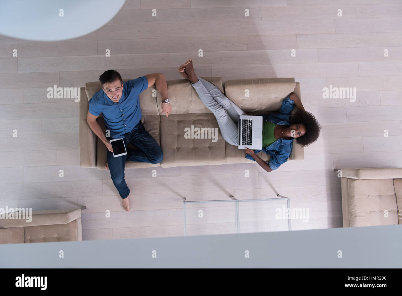 Young multiethnic couple relaxes in the luxury living room, using a ...
