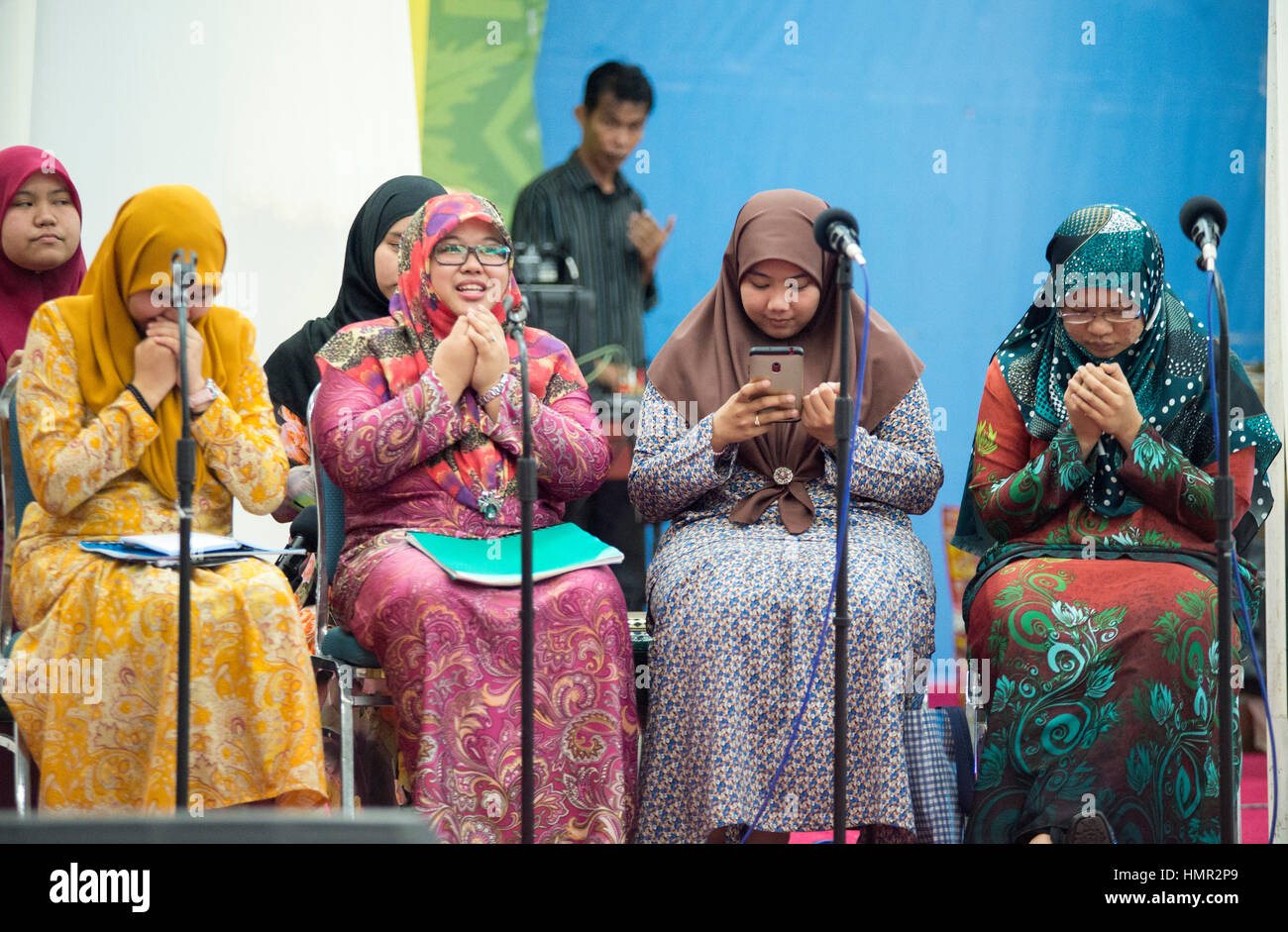 Female singers are seen praying, whilst one checks her phone at a ...