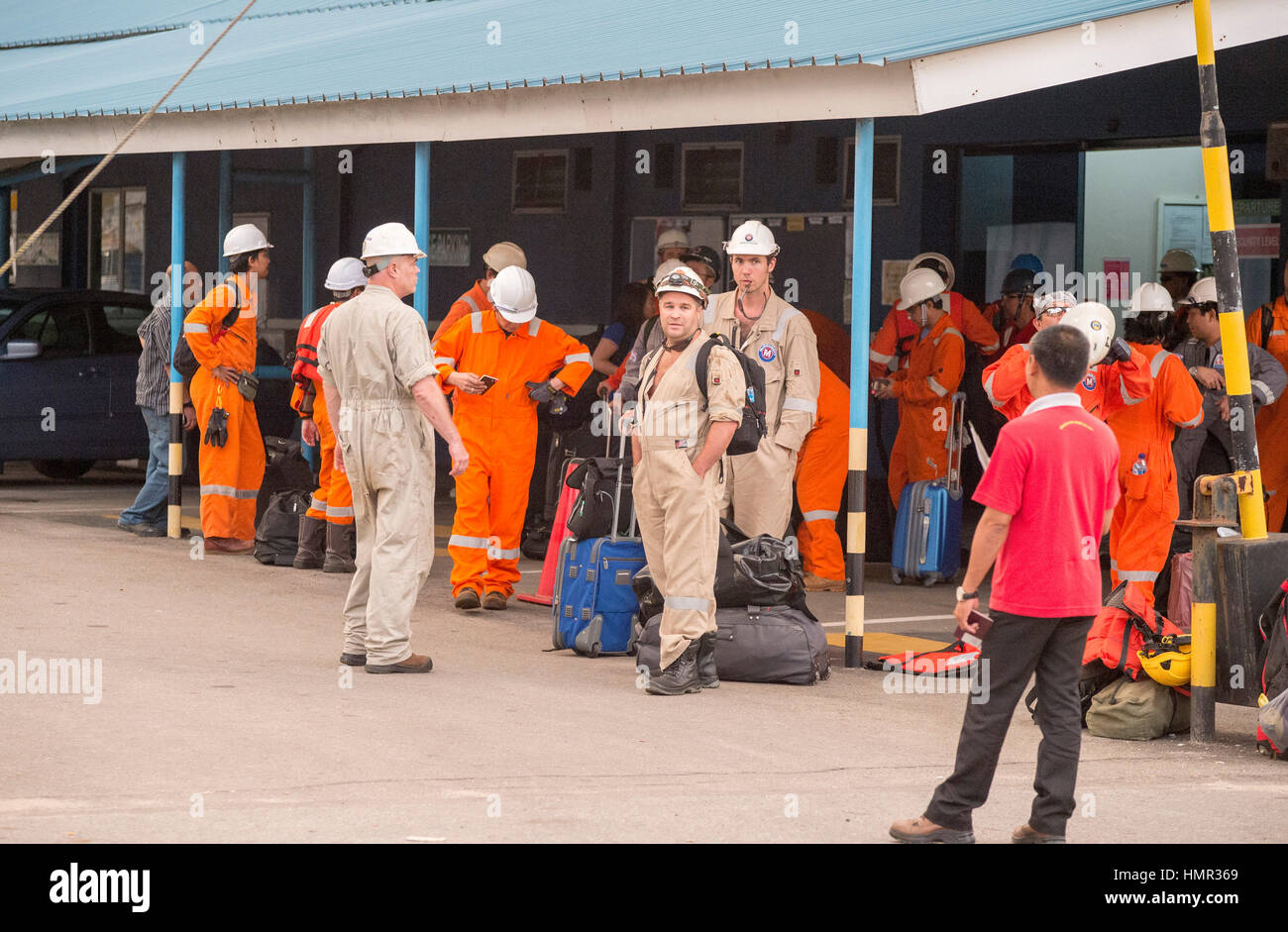 Oil workers in orange overalls are seen after their shift transfering ...