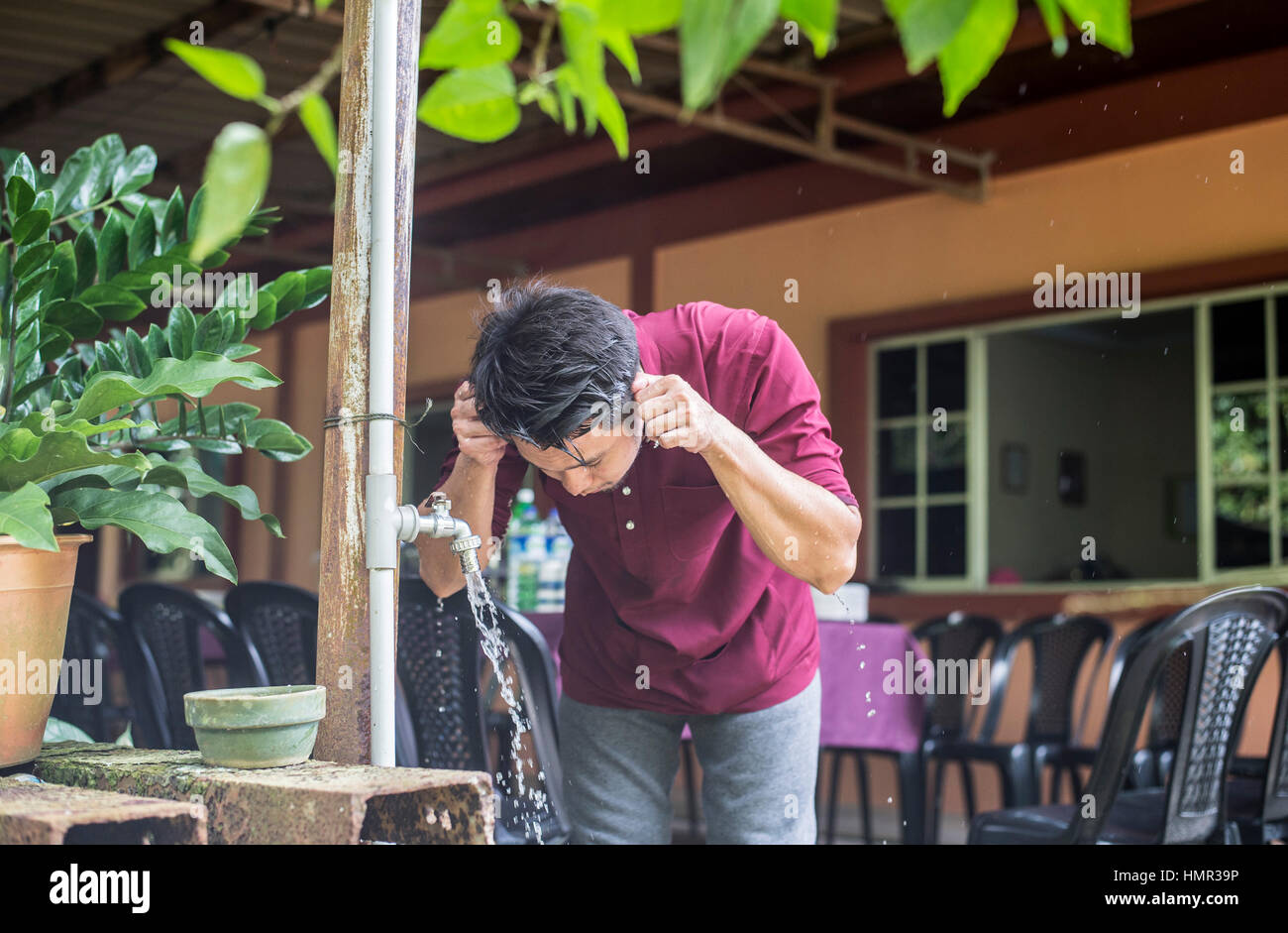 A muslim man is performing the ritual washing of his body before prayer ...