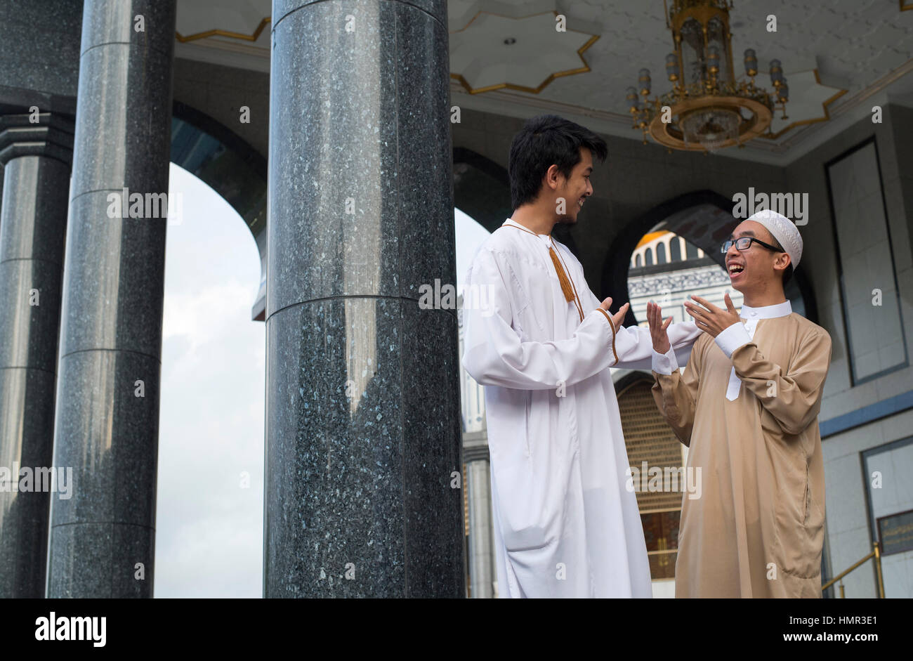 Two young muslim men are engaged in animated conversation at the ...