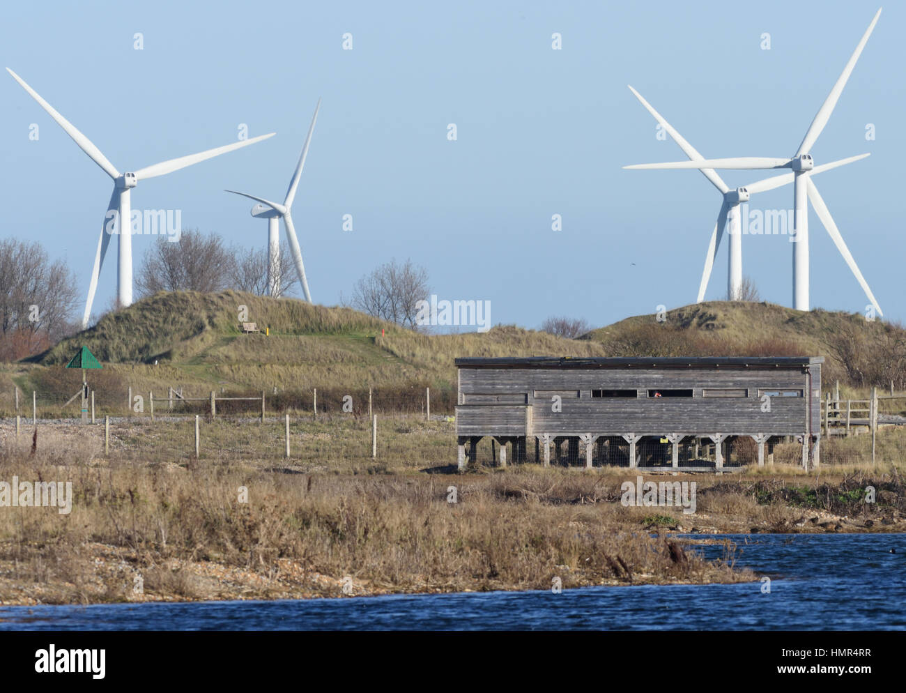 A bird watching hide in the Rye Harbour Nature Reserve is dwarfed by ...