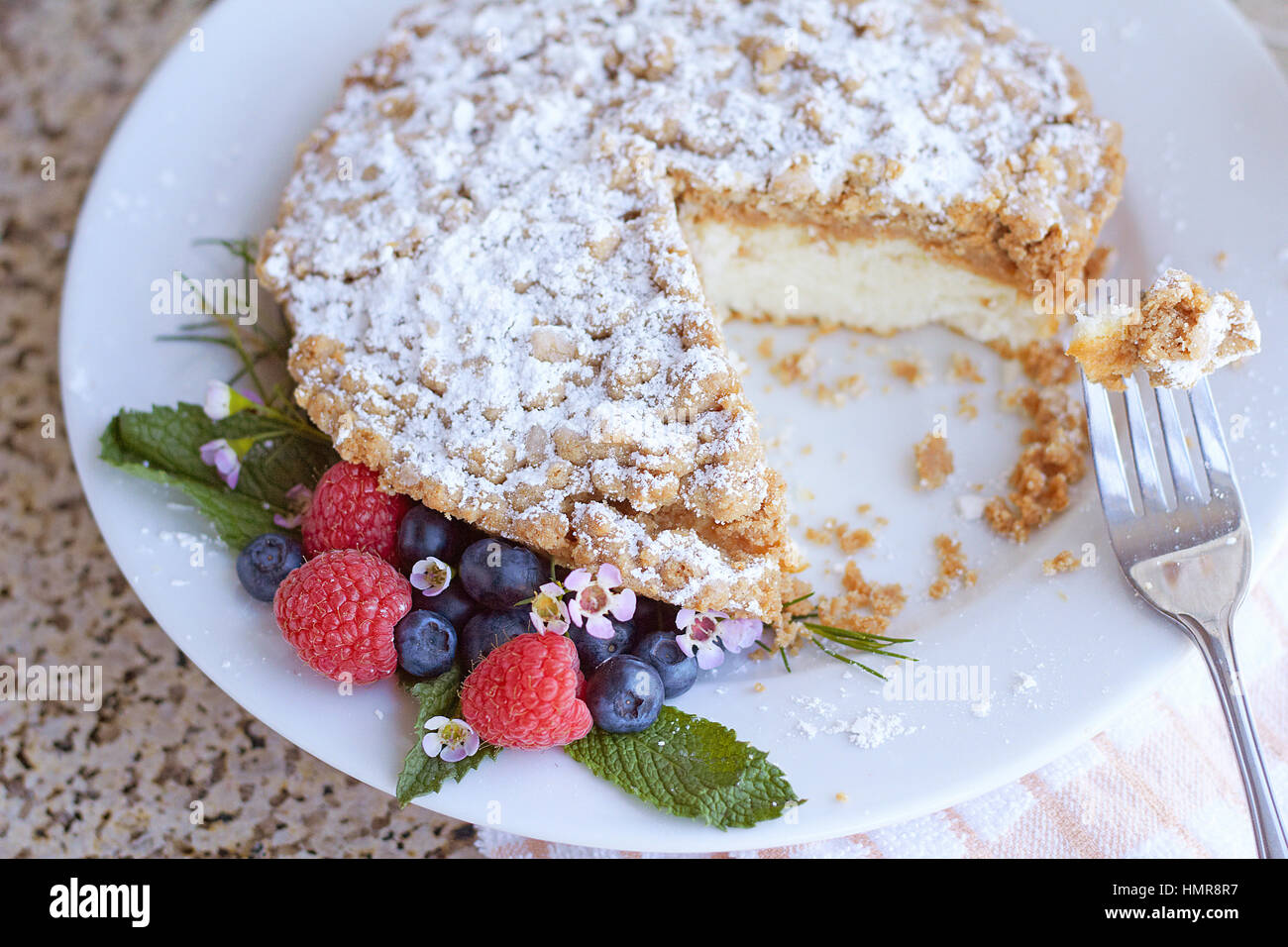 Round coffee cake dusted with powdered sugar and with a slice missing ...