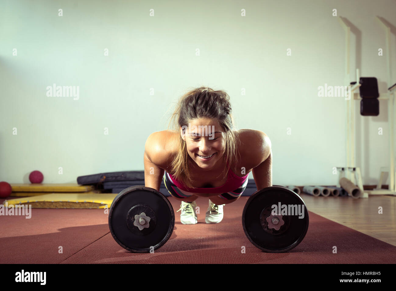 Girl doing push ups with dumbbell indoors Stock Photo - Alamy