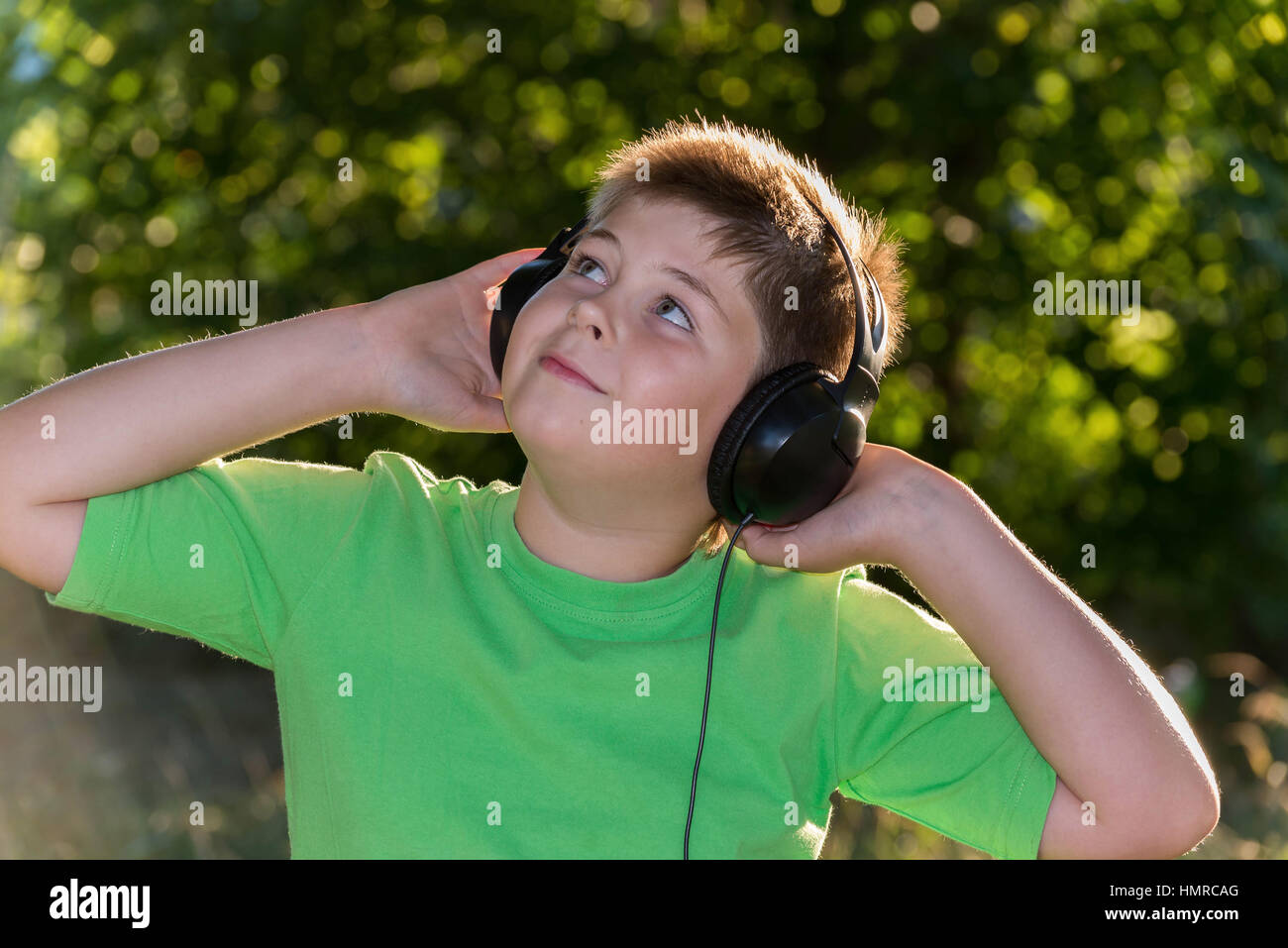 Cheerful boy listening to music with headphones in park Stock Photo - Alamy