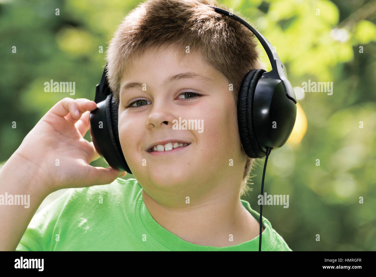 Cheerful boy listening to music with headphones in park Stock Photo - Alamy