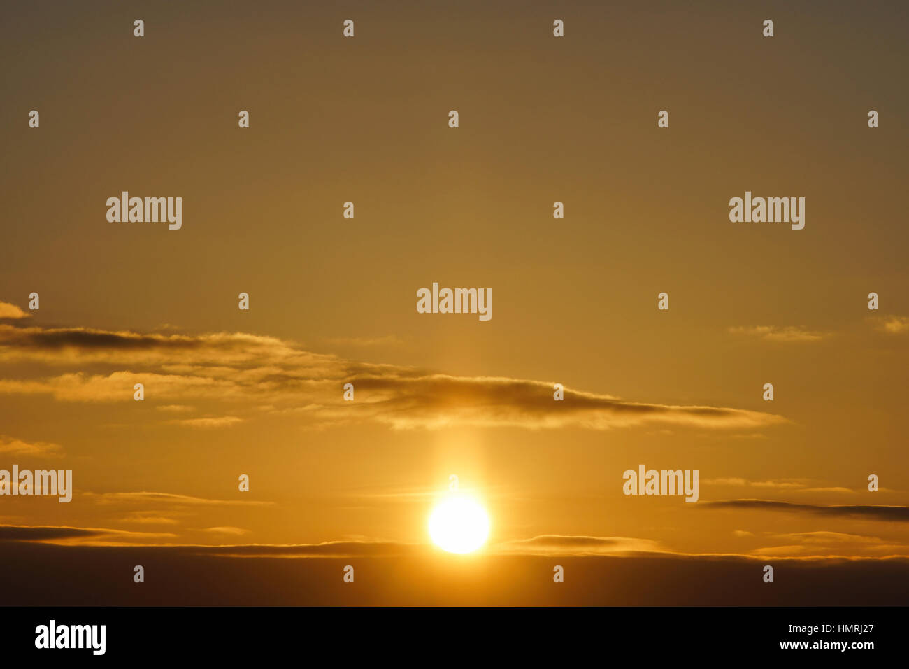 Morning sun breaking above horizon and clouds, golden sunrise scene ...