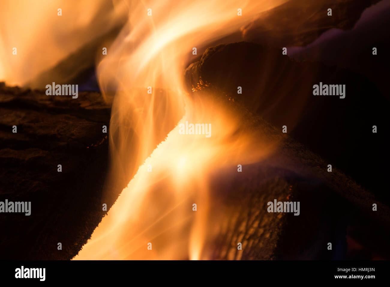 Orange and purple flames brightly glowing between two fire logs ...