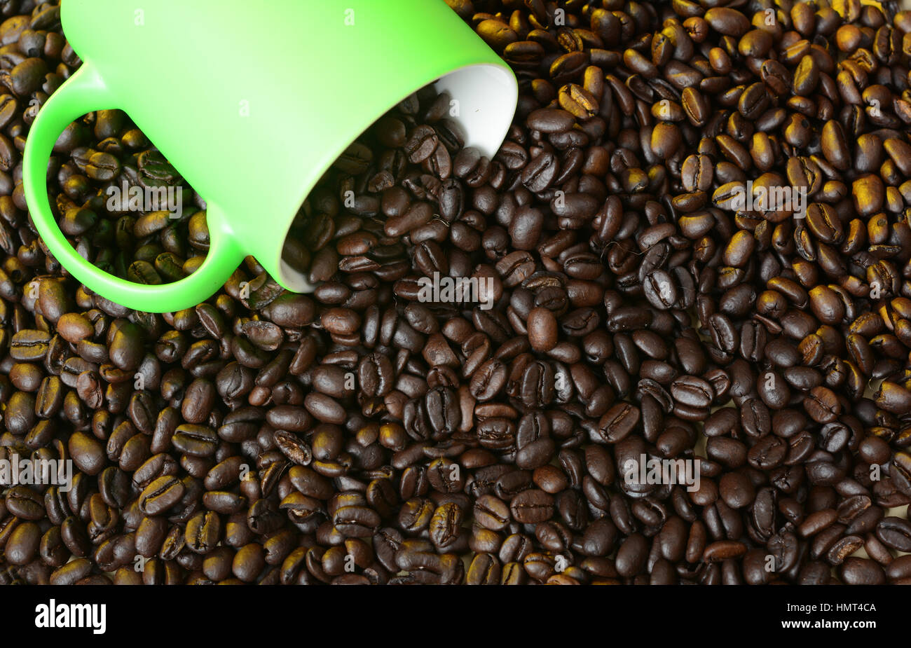 Roasted Coffee beans spill out of green cup Stock Photo - Alamy