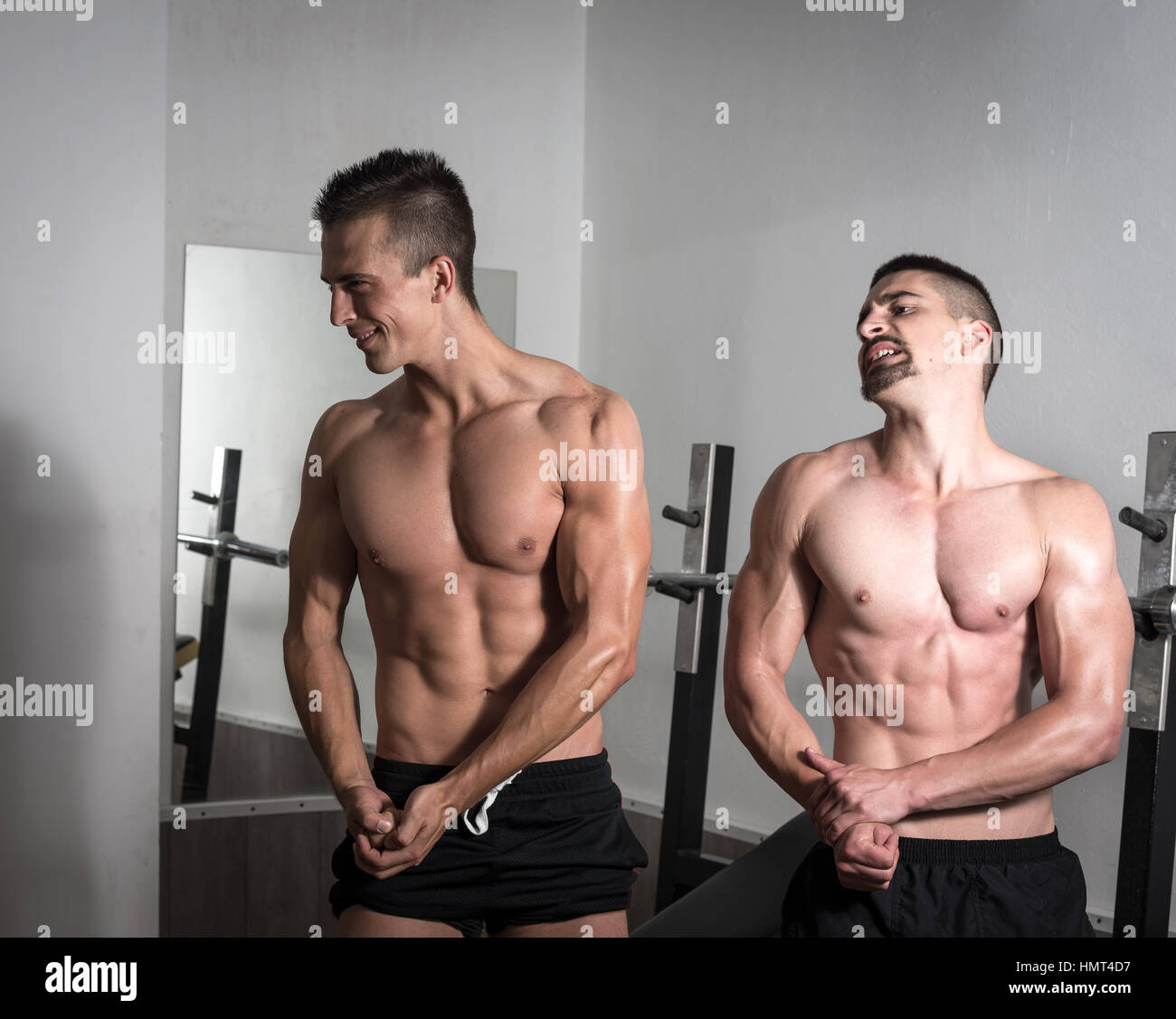 Two young men showing good shaped muscles in gym Stock Photo - Alamy