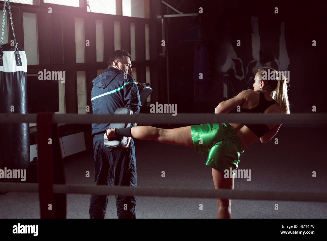 Young adult woman doing high kick during kickboxing training exercise ...