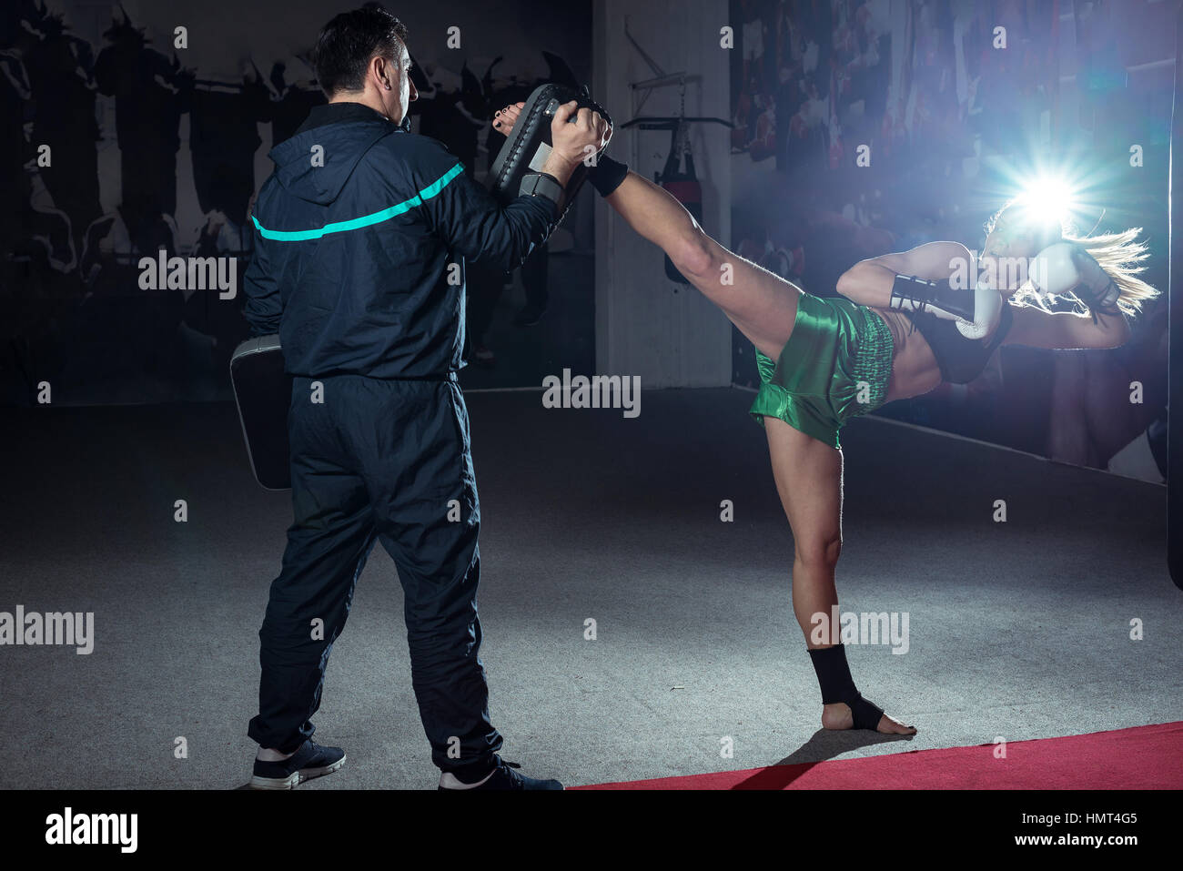 Young adult woman doing high kick during kickboxing training exercise ...