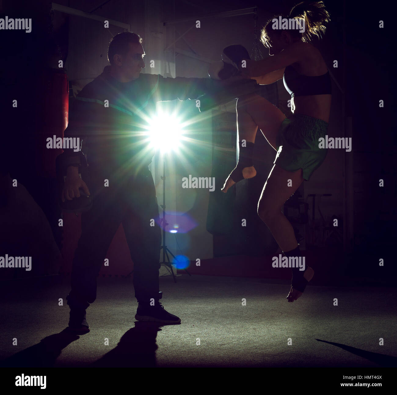 Girl doing knee kick exercise during kickboxing training with personal ...