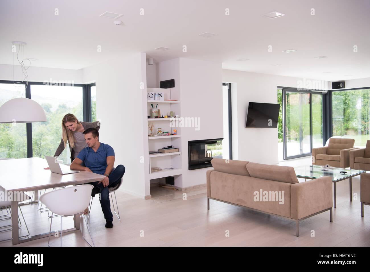 Young couple using laptop computer at luxury home together, looking at ...