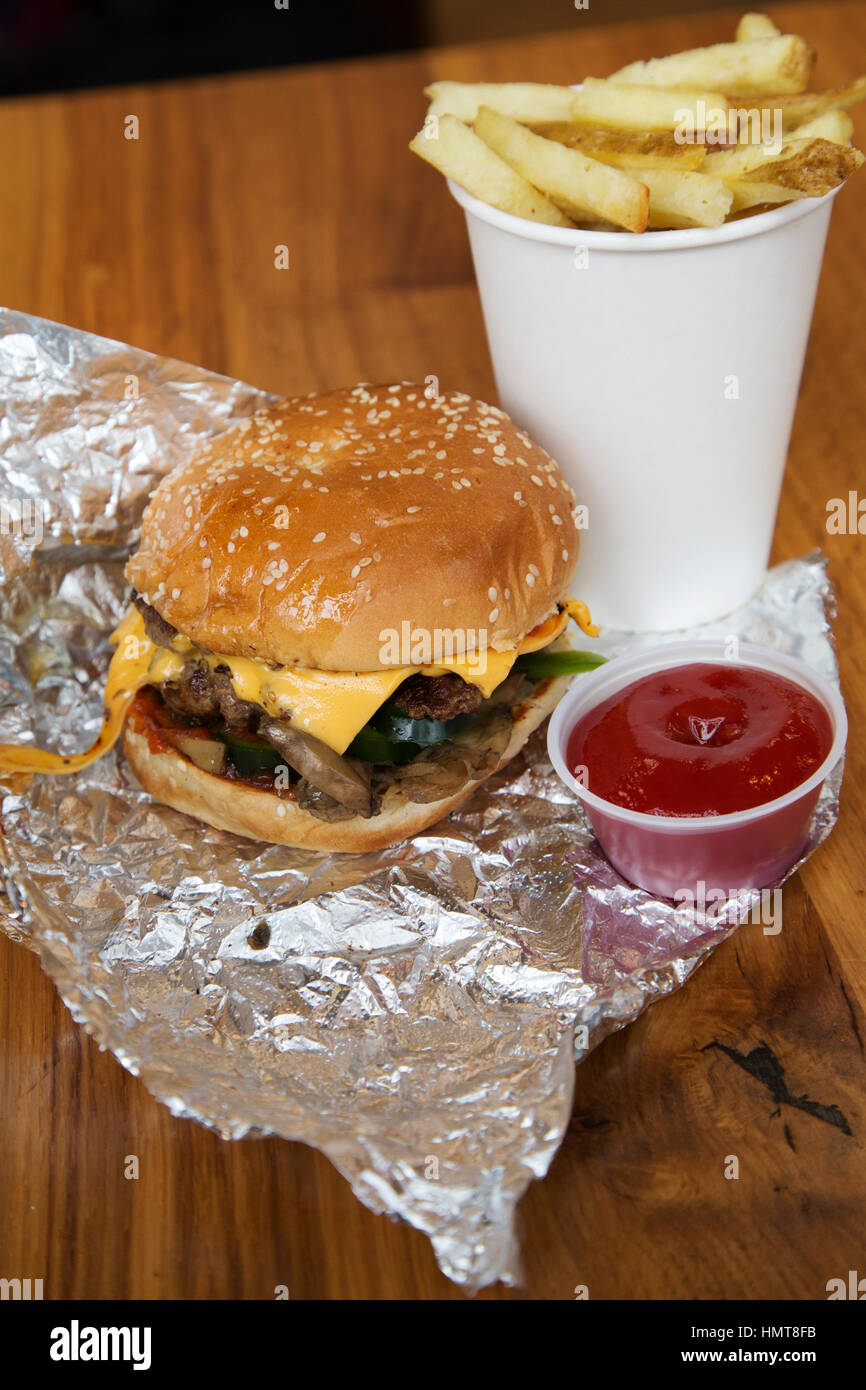 A gourmet burger served with fries and ketchup. The cheeseburger is one ...