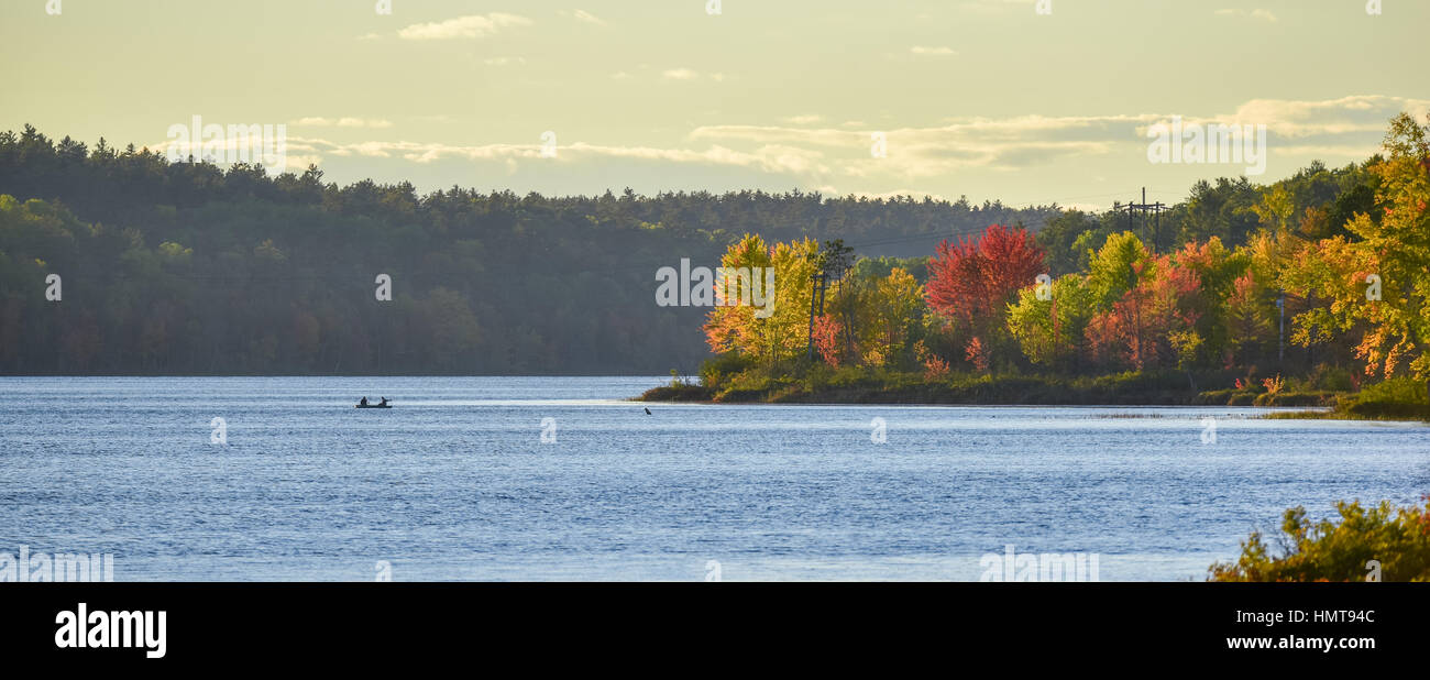 Two men in the distance floating in a small fishing boat, casting lines ...