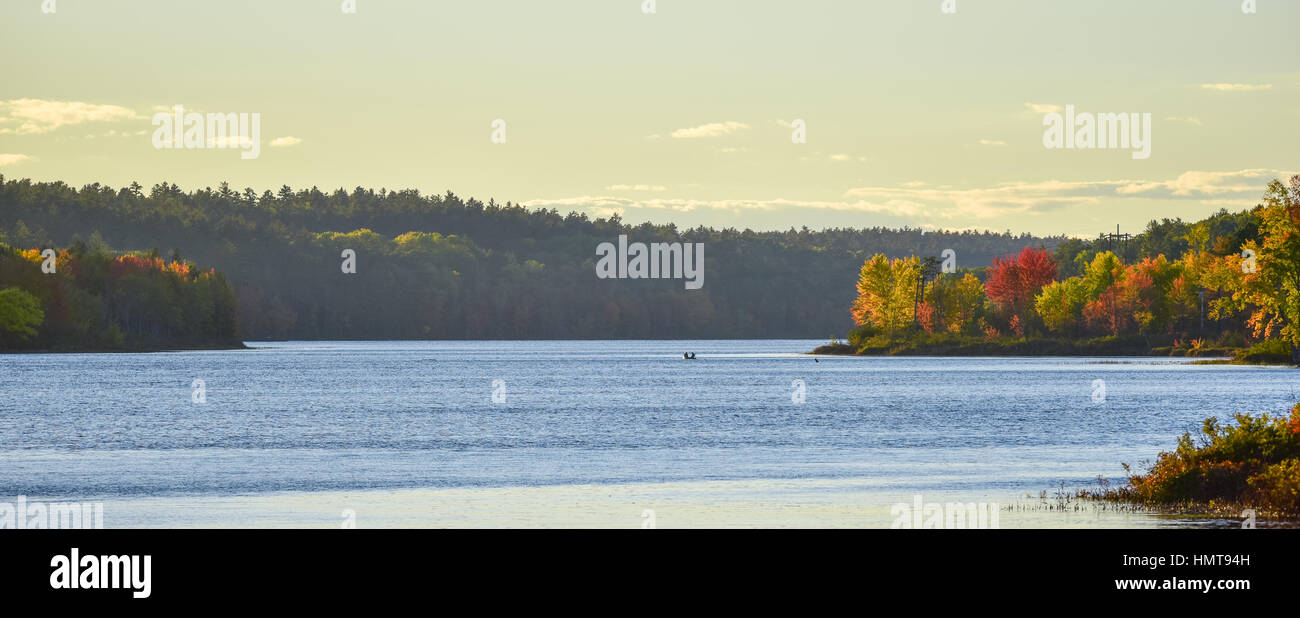 Two men in the distance floating in a small fishing boat, casting lines ...