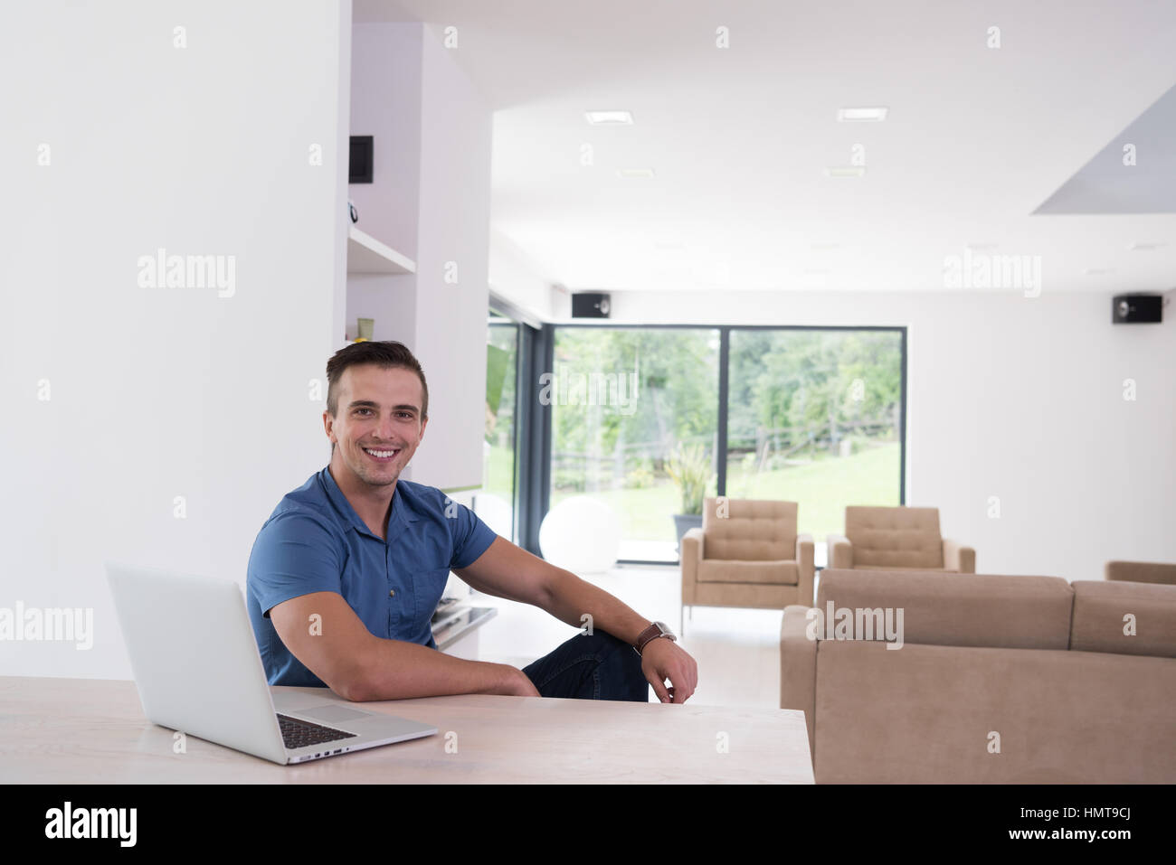 Young man with his laptop computer at his luxury modern home, smiling ...