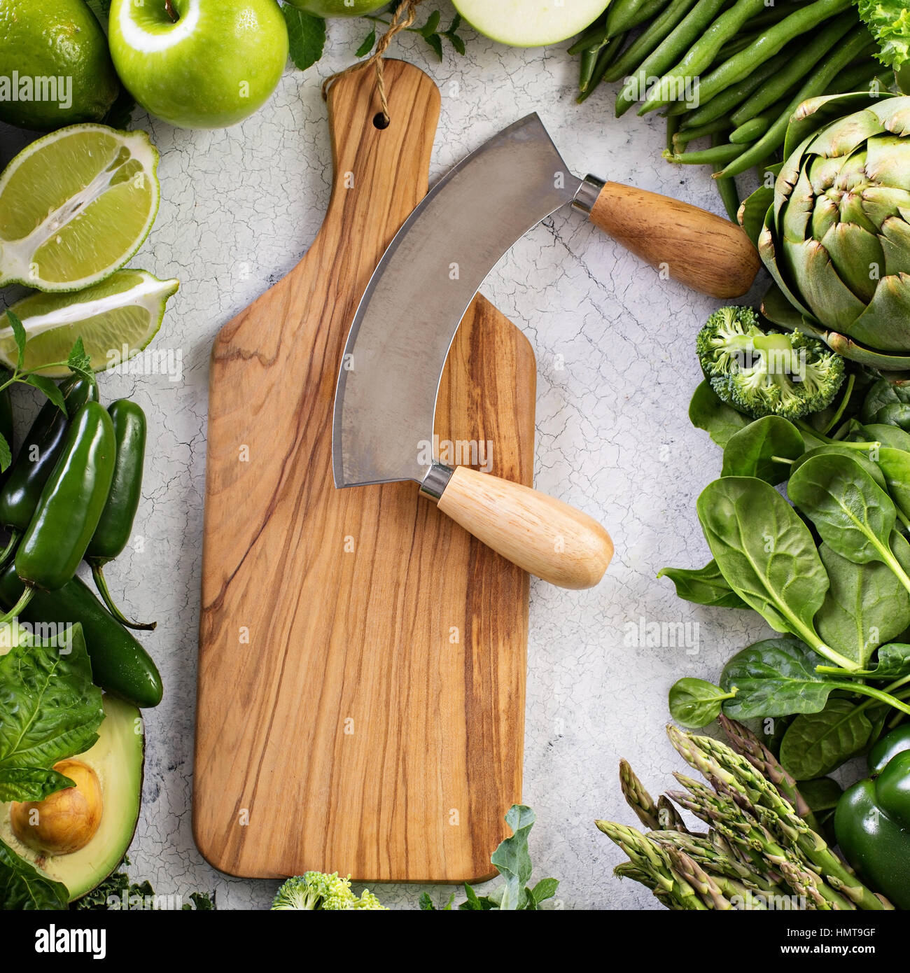 Variety of green vegetables and fruits copyspace with cutting board on ...