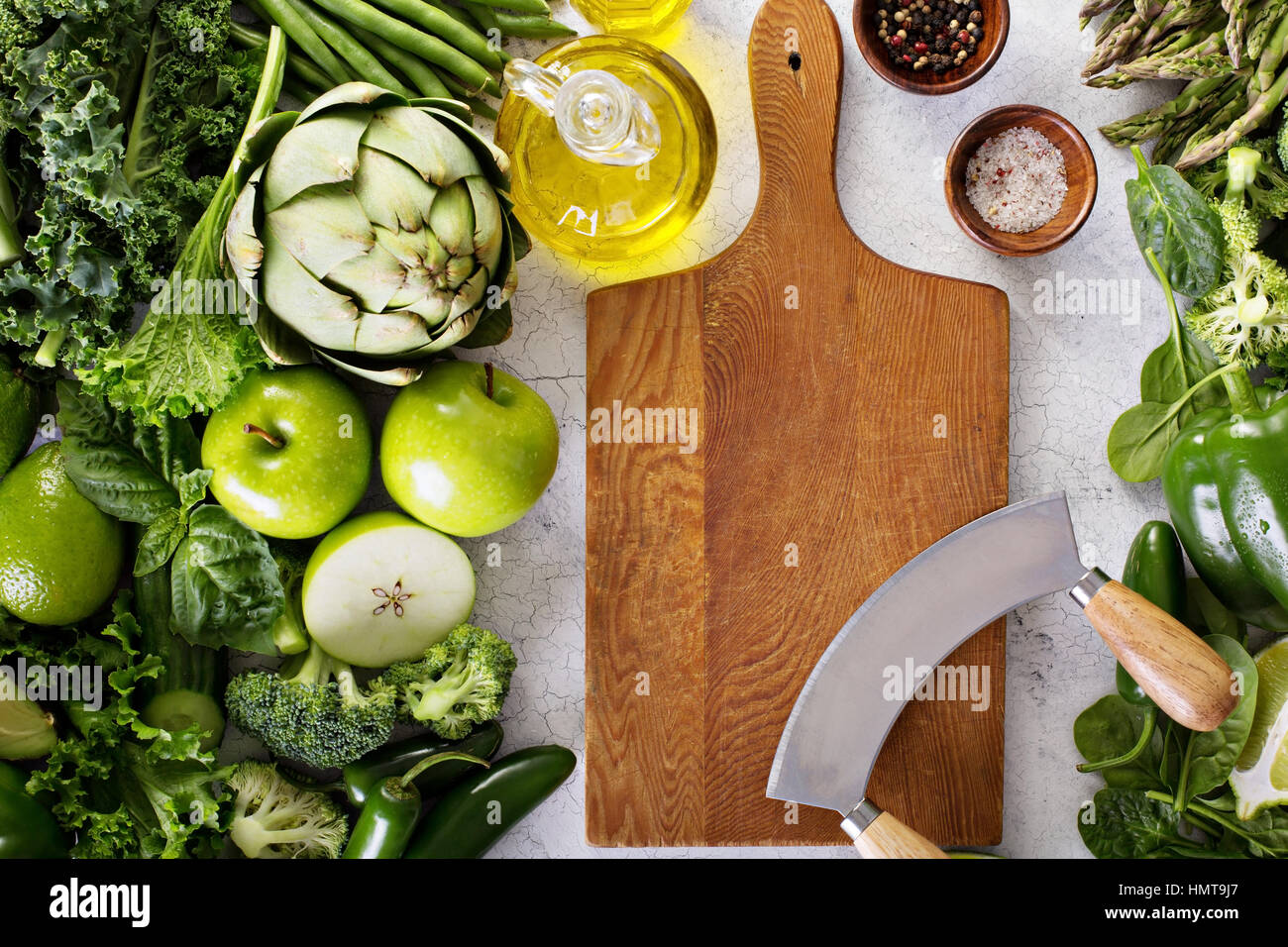 Variety of green vegetables and fruits copyspace with cutting board on ...