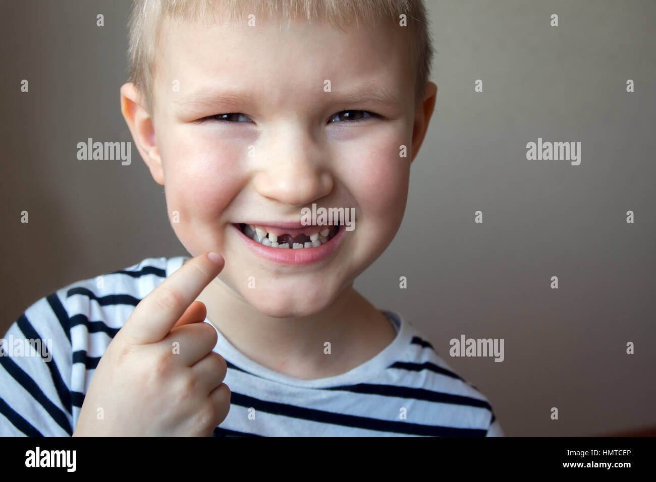 Young boy smiling, showing off his first missing milk tooth (teeth), close up portrait ...