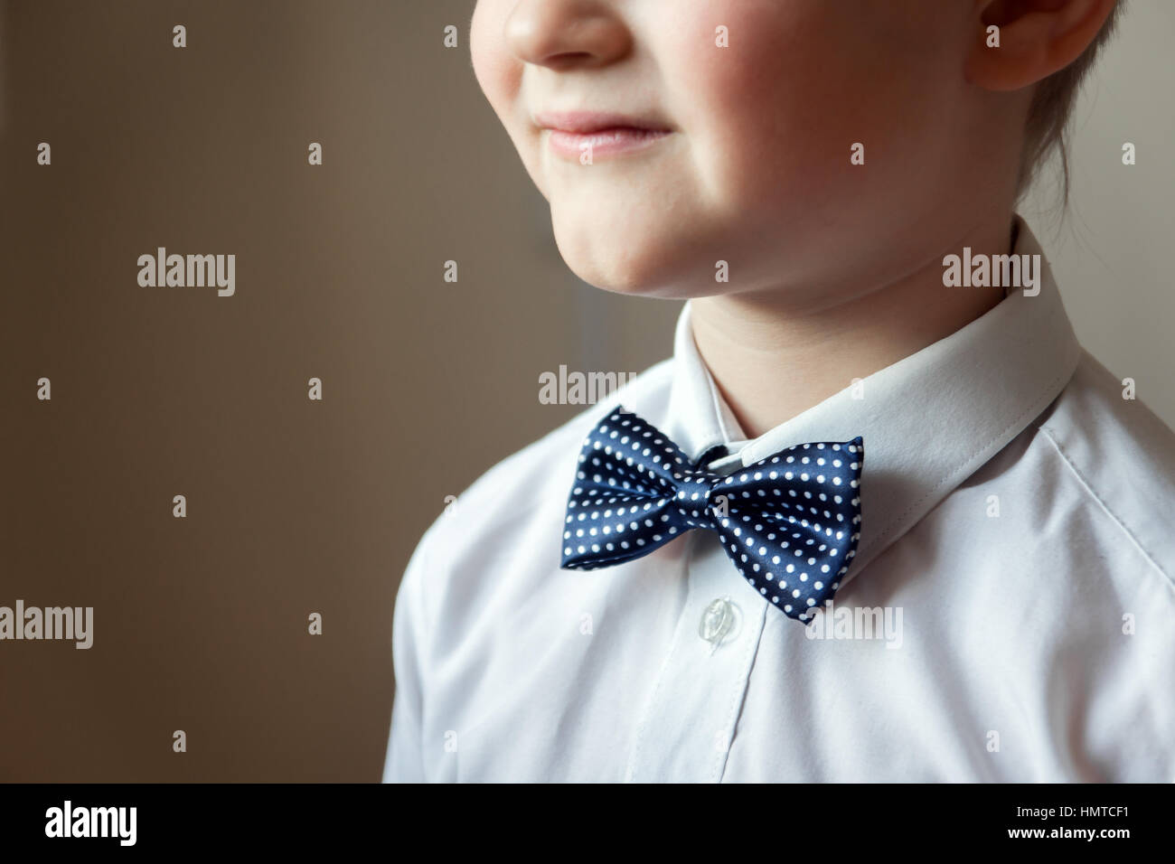 Smiling young boy with blue bow tie, portrait with copy space ...