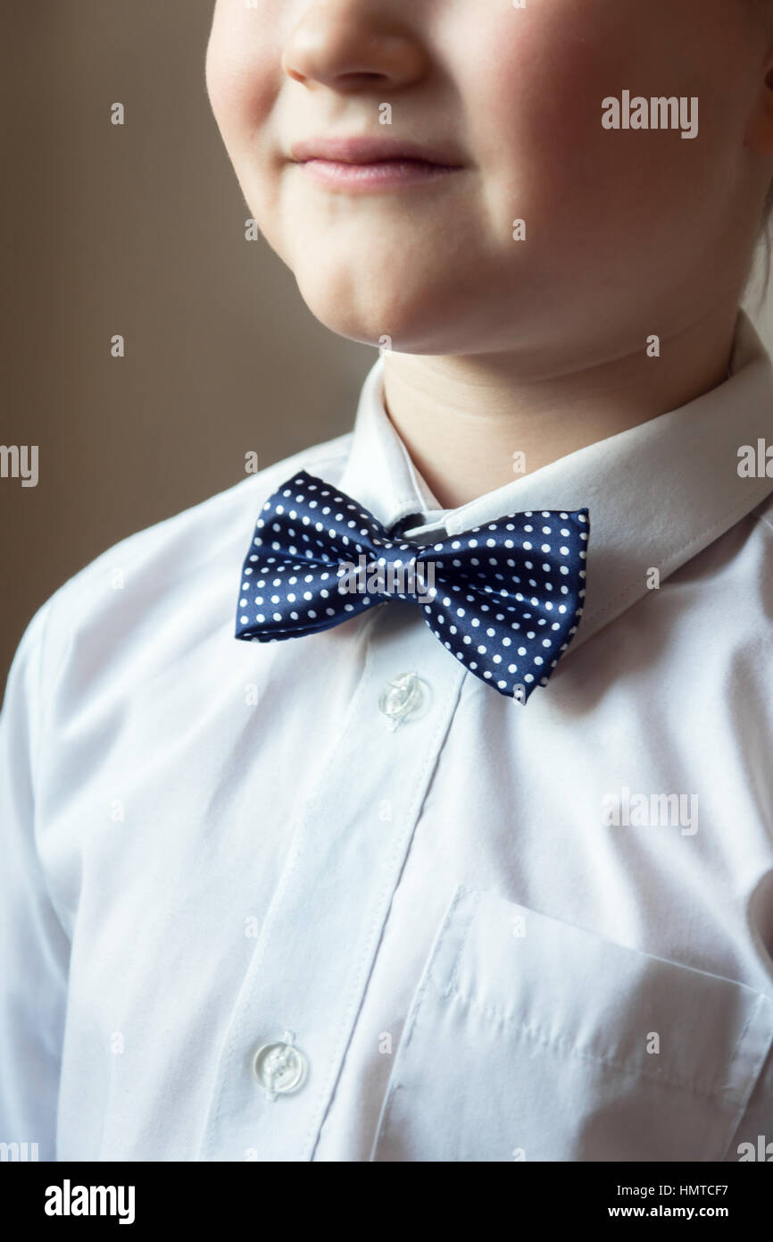 Smiling young boy with blue bow tie, portrait with copy space ...