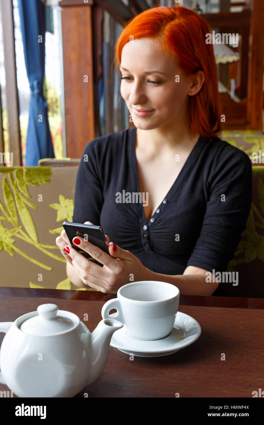 Portrait of beautiful girl in hat using her mobile phone in cafe ...