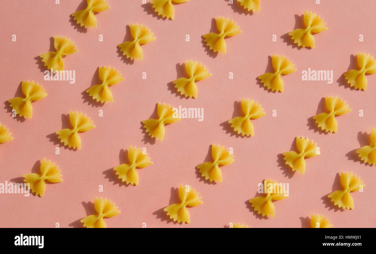 Maсaroni or pasta bow shape in row on pink background Stock Photo - Alamy
