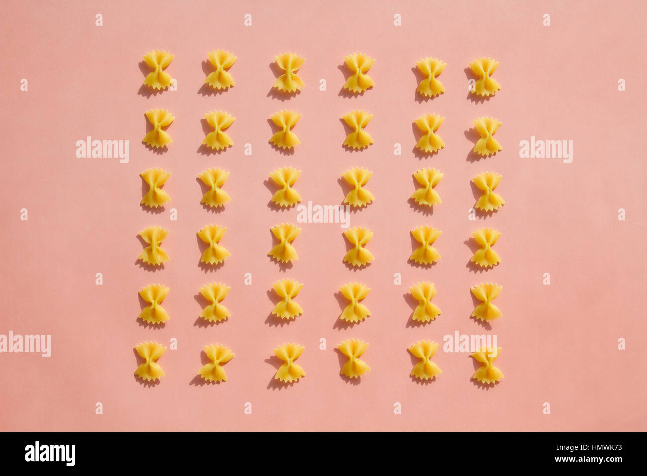 Maсaroni or pasta bow shape in row on pink background Stock Photo - Alamy