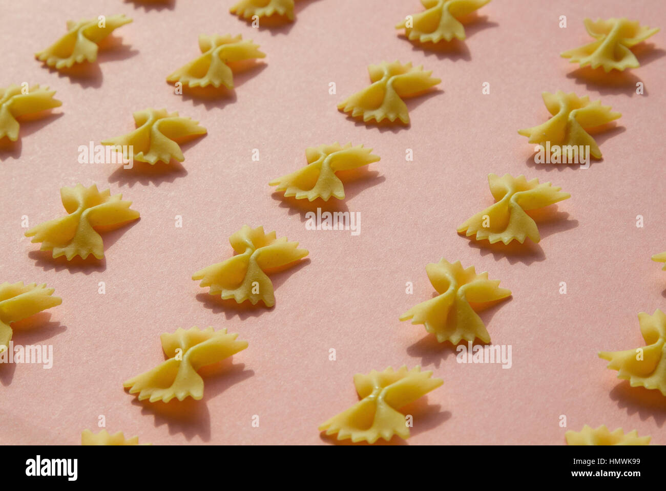 Maсaroni or pasta bow shape in row on pink background Stock Photo - Alamy