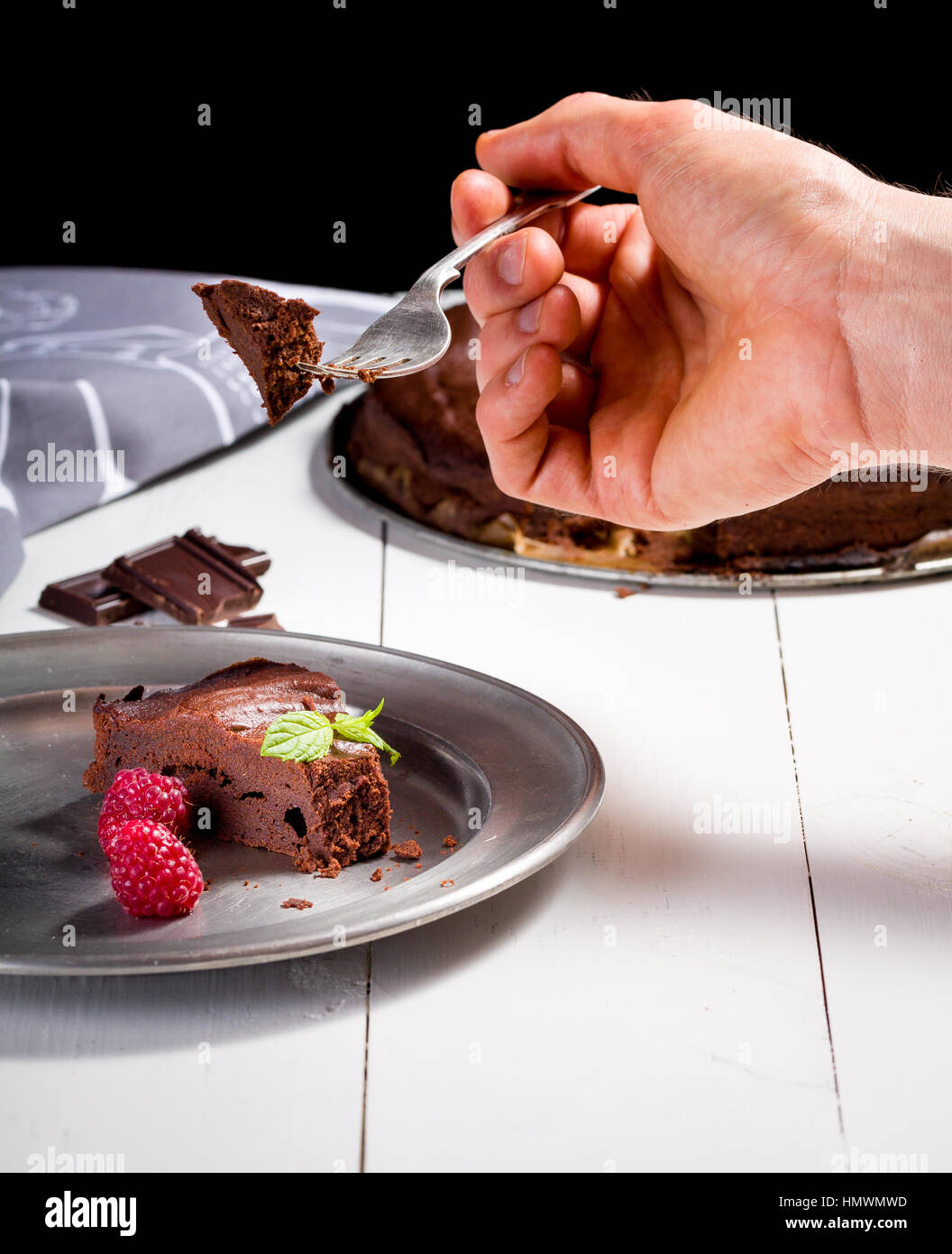 Man hand try a piece of cake chocolate brownie with raspberries and ...