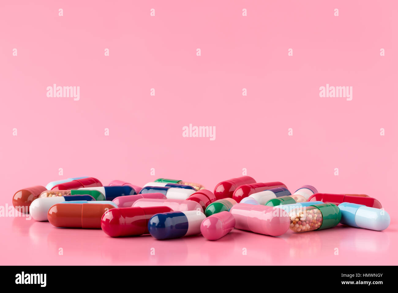 Heap of colorful drugs and pills on pink background Stock Photo - Alamy