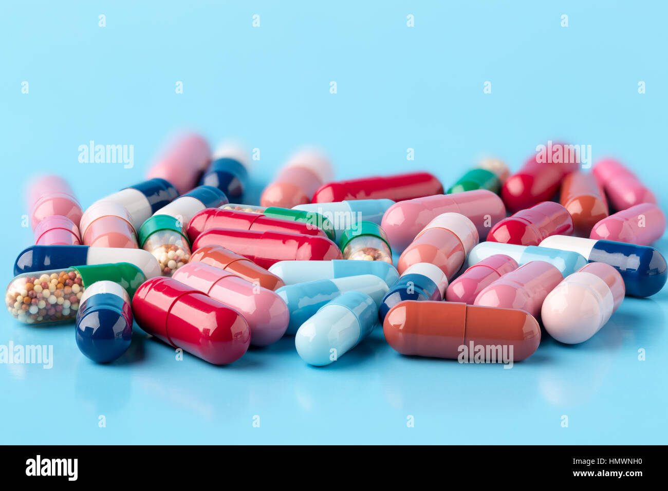 Heap of colorful drugs and pills on blue background Stock Photo - Alamy